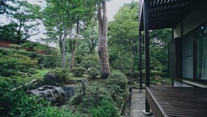 Um jardim japonês tradicional com um banco de madeira, caminhos de pedra e diversas plantas.