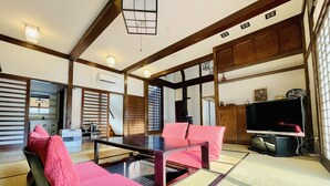 Quarto em estilo japonês tradicional, com tatames, uma mesa baixa e almofadas vermelhas.