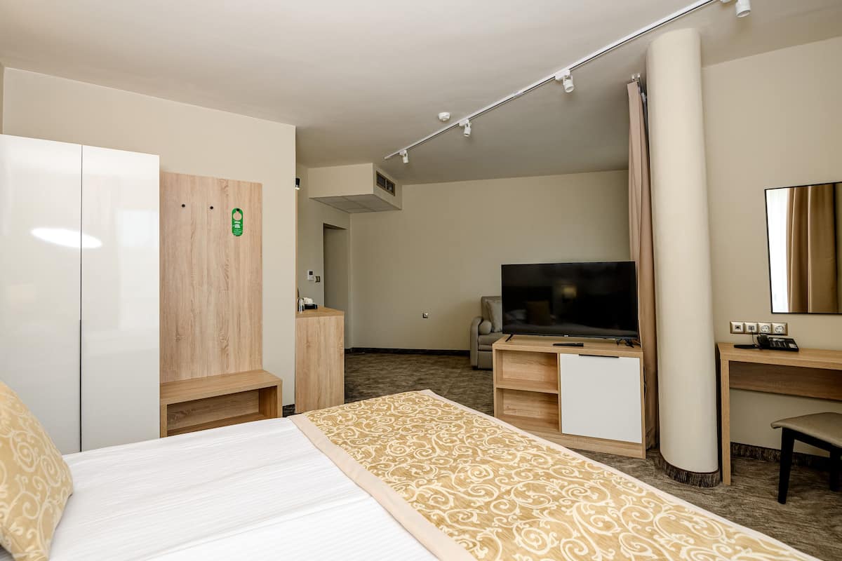 Quarto de hotel com cama, escrivaninha, televisão e guarda-roupa.