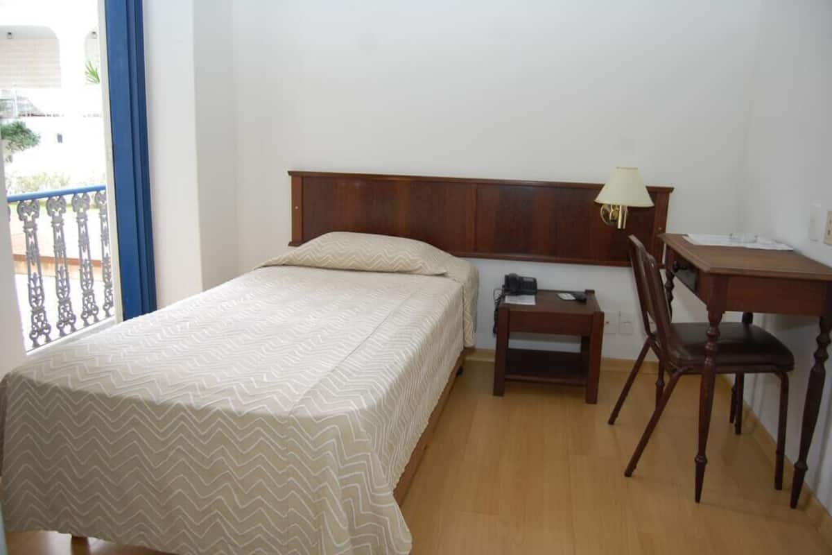 Quarto com cama, escrivaninha, cadeira e abajur.