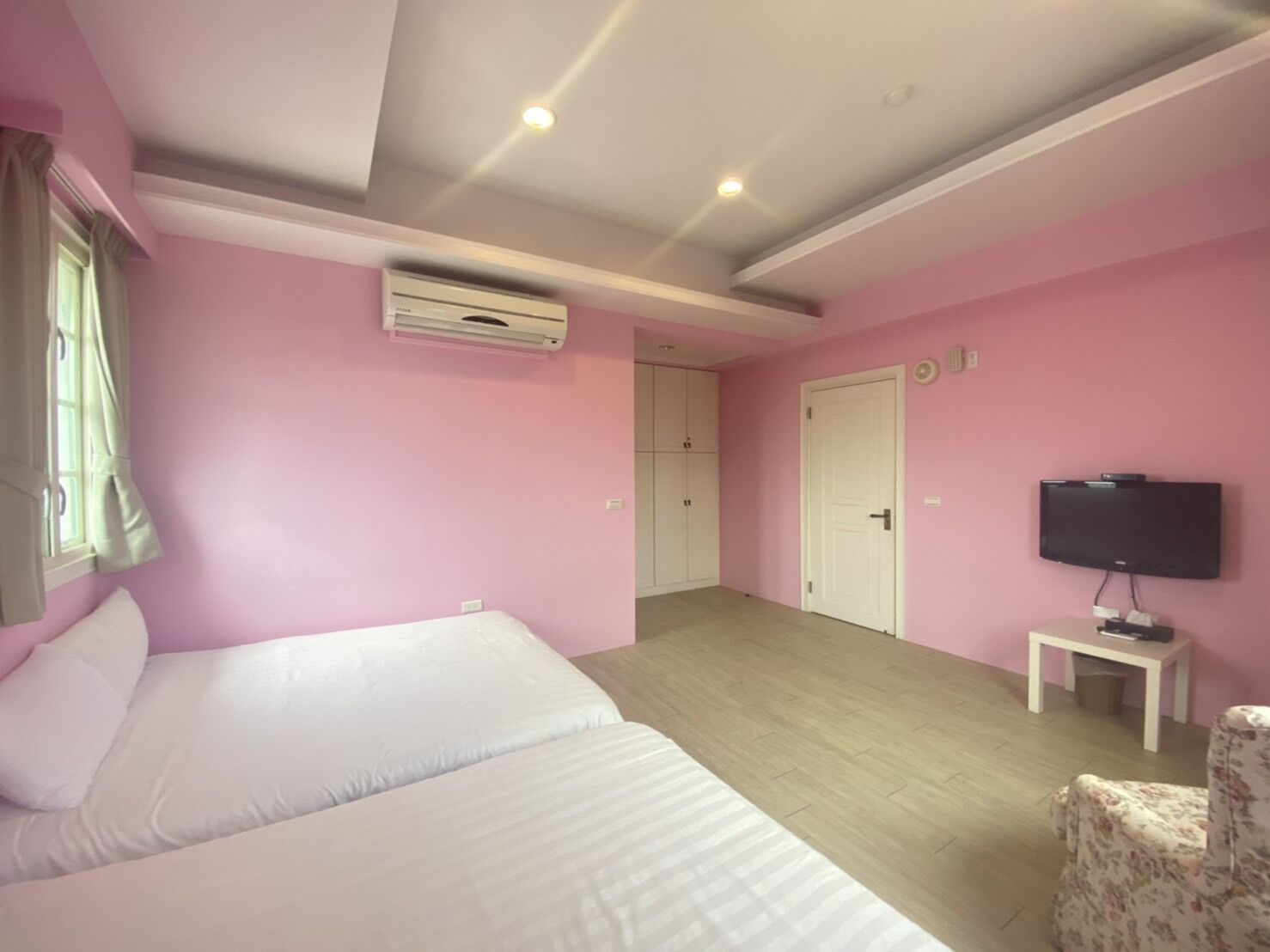 Quarto com cama, televisão, escrivaninha e guarda-roupa.