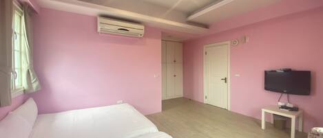 Quarto com cama, televisão, escrivaninha e guarda-roupa.