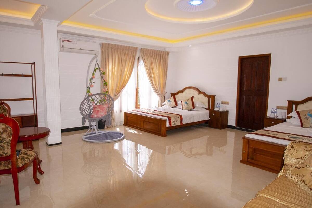 Quarto de hotel com uma cama grande, uma mesa de cabeceira, uma cadeira e uma pequena mesa redonda.