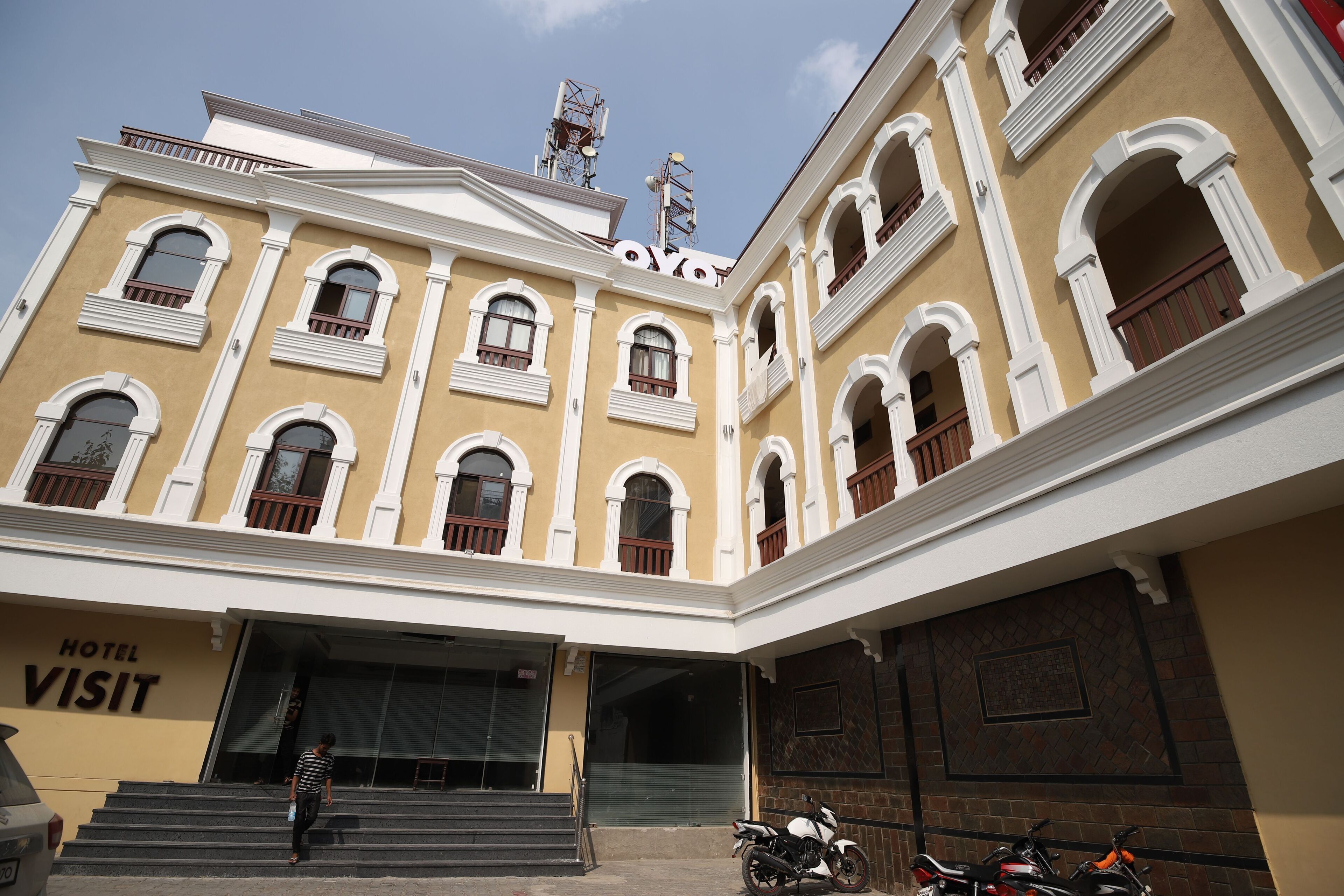 Um hotel com estilo arquitetônico clássico, com janelas em arco e uma entrada central com degraus até a porta.