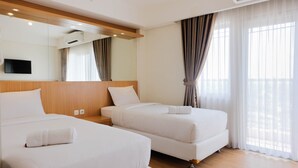 Quarto de hotel com duas camas, um espelho grande, um aparelho de ar condicionado e uma TV na parede.