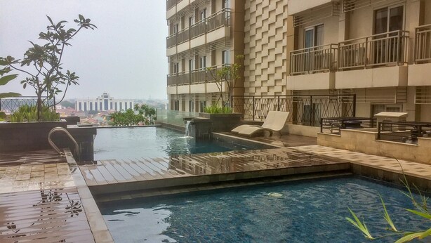 Uma área de piscina no terraço com vista desobstruída para o horizonte da cidade.