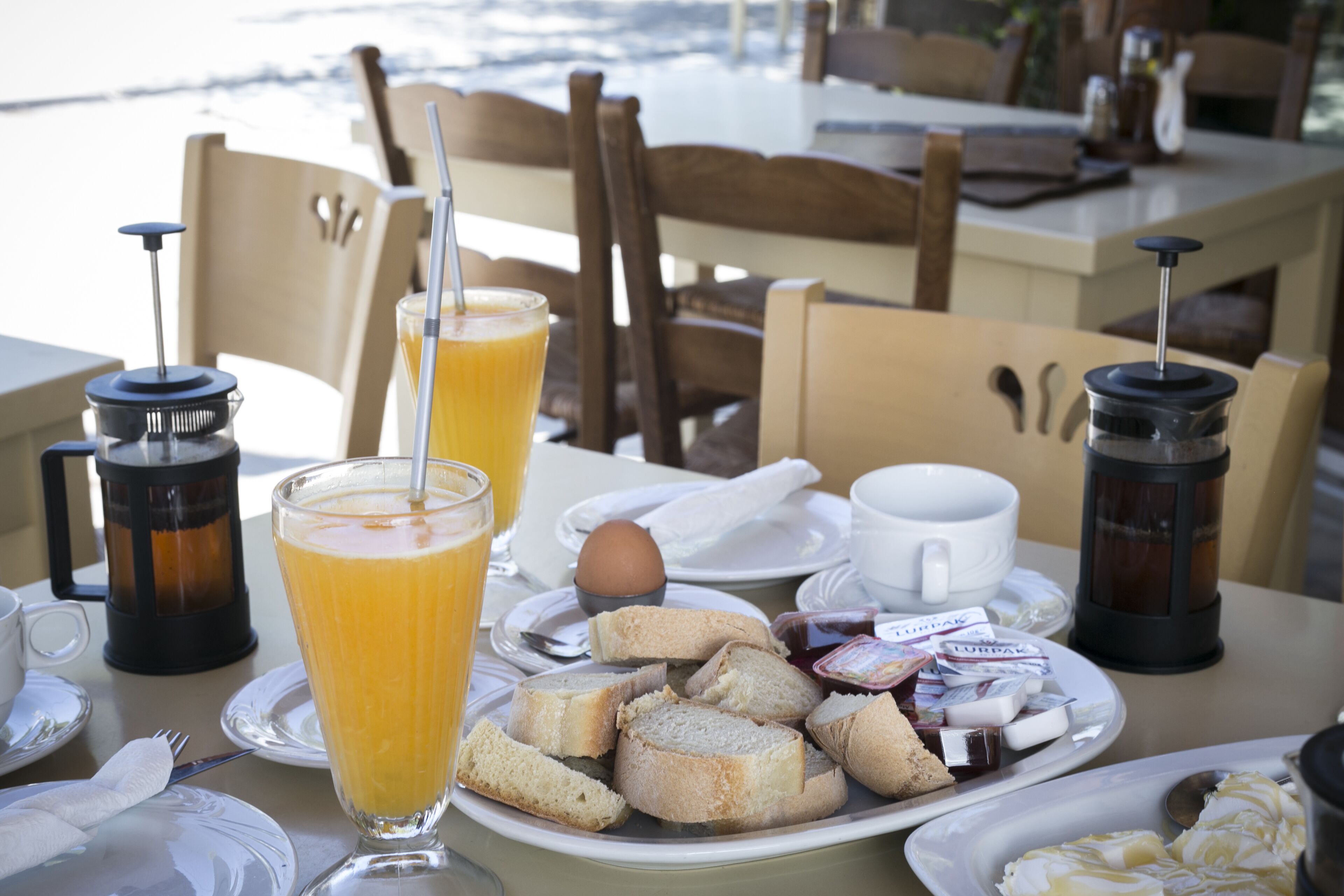 Uma mesa de café da manhã com torradas, um copo de suco de laranja, uma xícara e uma cafeteira.