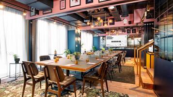 Uma sala de conferências com uma mesa comprida, cadeiras e uma tela de projetor.