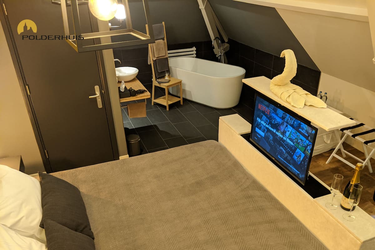 Casa de banho moderna com banheira, pia e sanita. Uma televisão exibe a interface da Netflix.