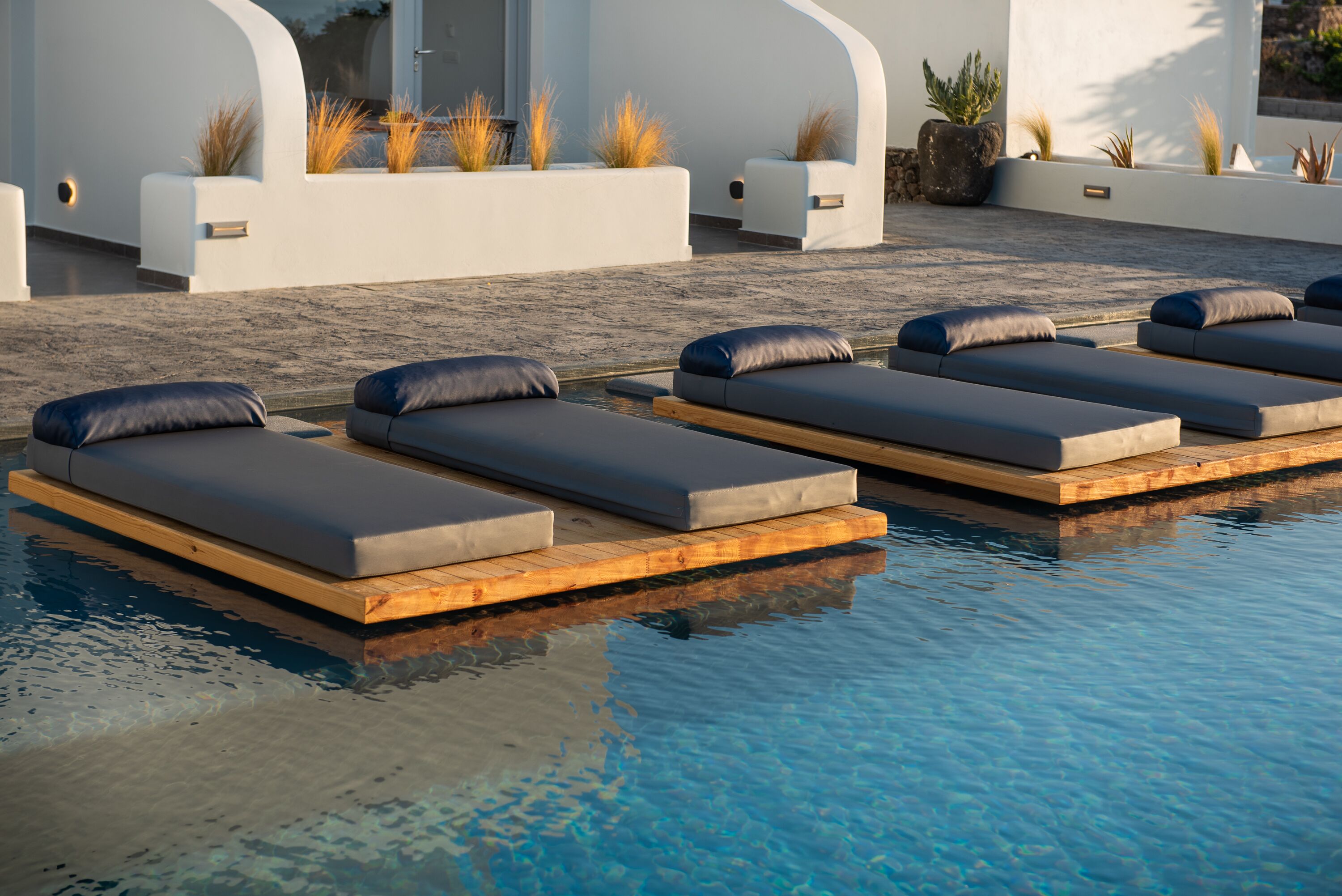 Área da piscina com espreguiçadeiras e vasos de plantas.