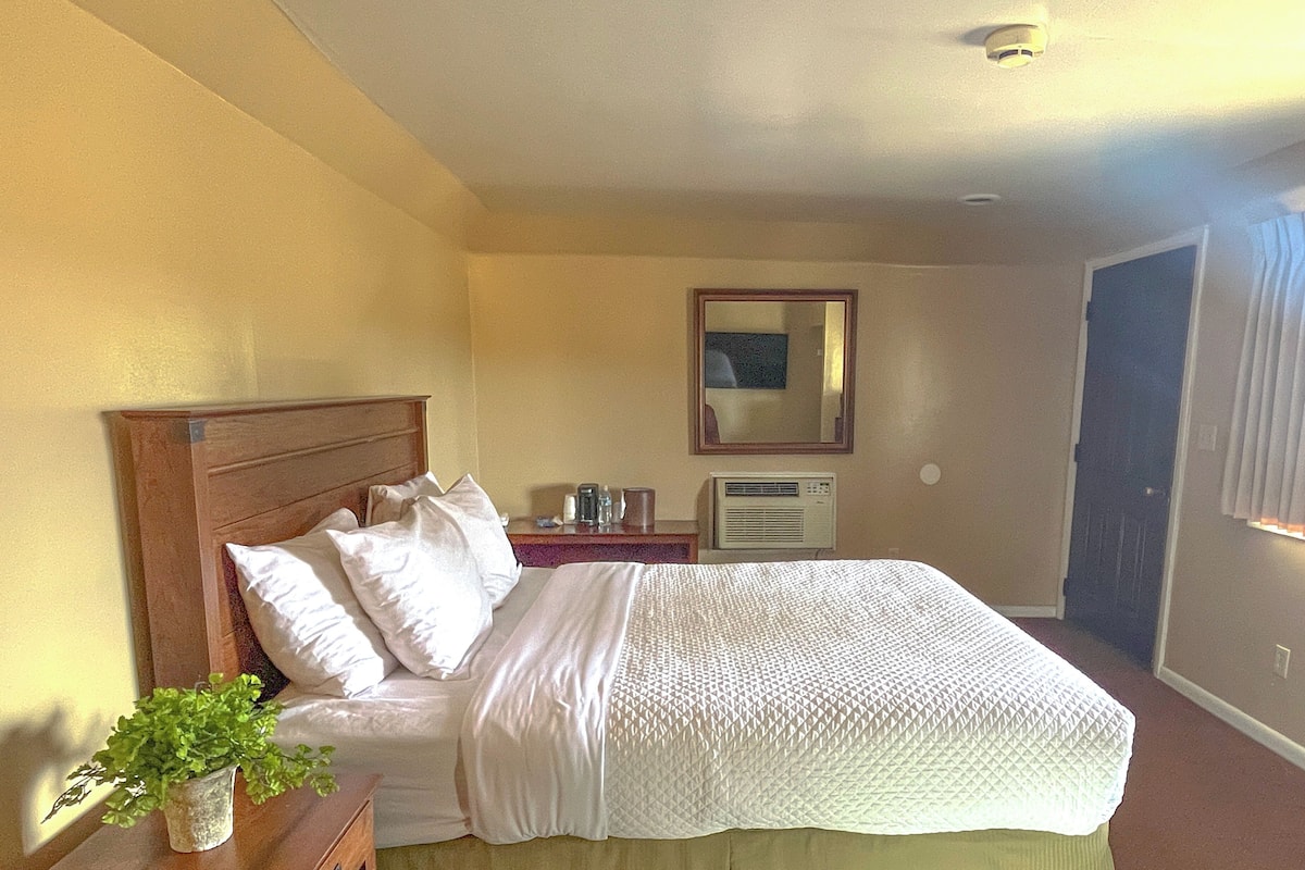 Quarto de hotel com cama, mesa de cabeceira e espelho.