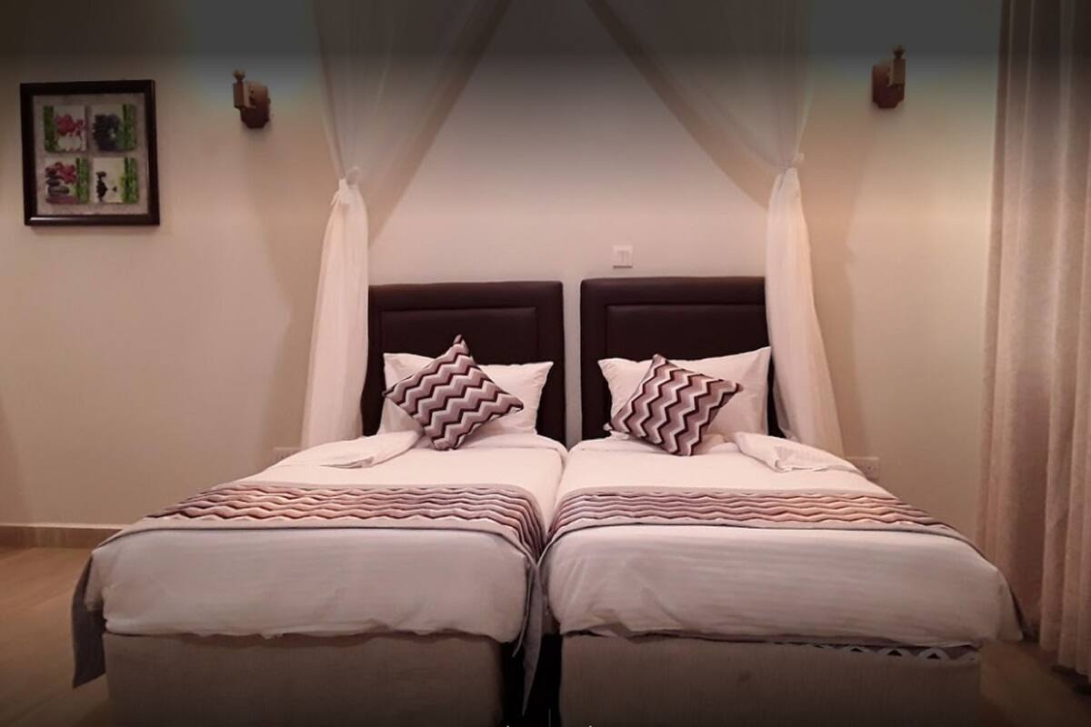 Uma cama de casal com dossel, duas mesas de cabeceira e um quadro na parede.