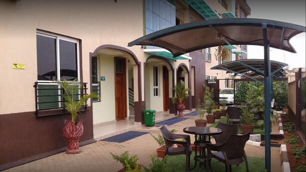 Pátio com área de estar ao ar livre, espaço coberto e entrada de um edifício.