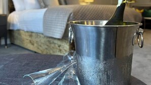 Um balde de metal com uma garrafa dentro, colocado sobre uma mesa em quarto de hotel.