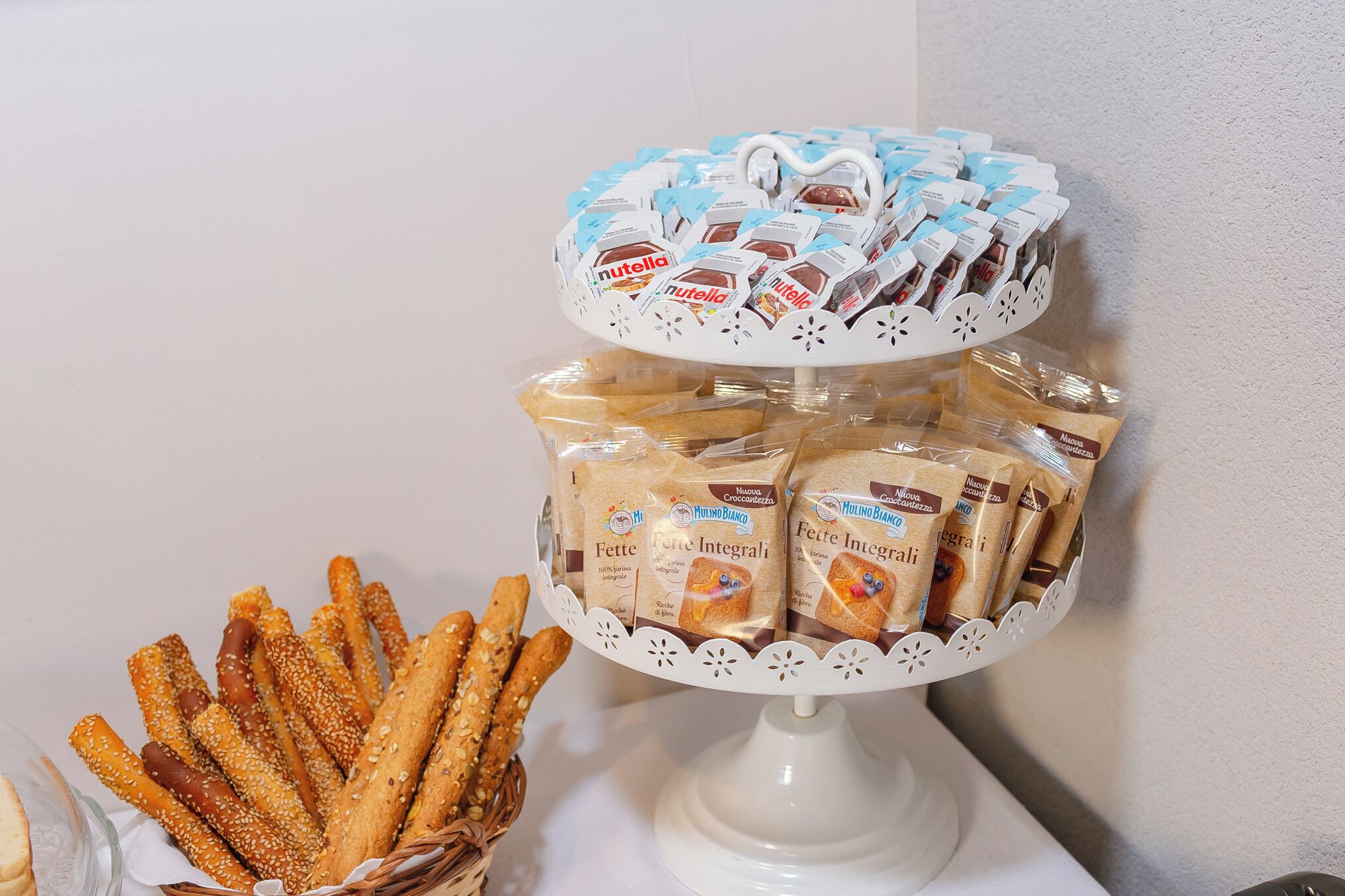 Exposição de lanches embalados e pão sobre um suporte branco.
