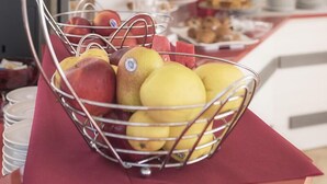 Uma cesta de frutas com bananas e maçãs sobre uma mesa.