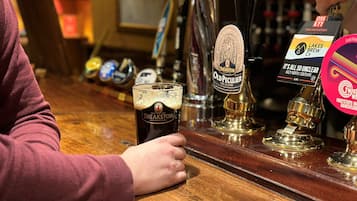 Um bar com um copo de cerveja, uma torneira de cerveja com a inscrição "Theakston Legendary Ale" e outra torneira com a inscrição "Lakes Brew Co. 5.3%".