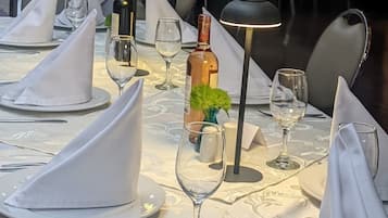 Mesa posta para refeição com guardanapos brancos, copos de vinho e talheres.