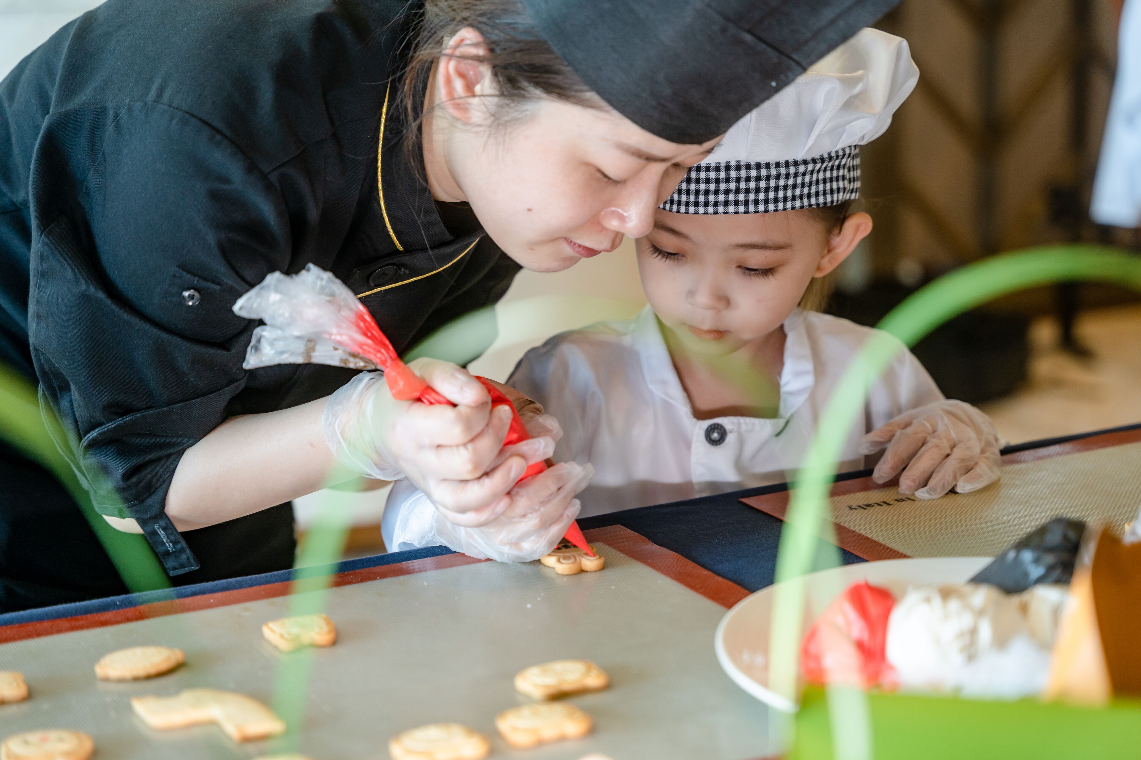 Uma pessoa vestida de chefe decorando biscoitos em uma assadeira.