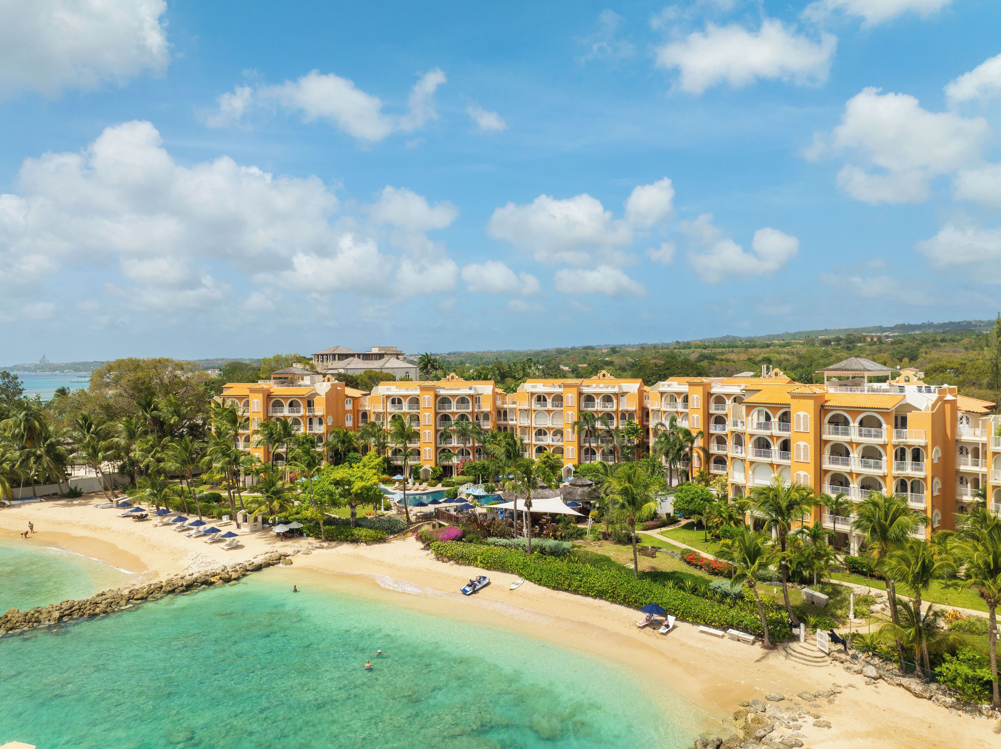 Resort com vários edifícios, praia e águas turquesa cristalinas.