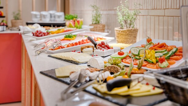 Buffet com diversos alimentos, incluindo queijos, frutas e legumes.