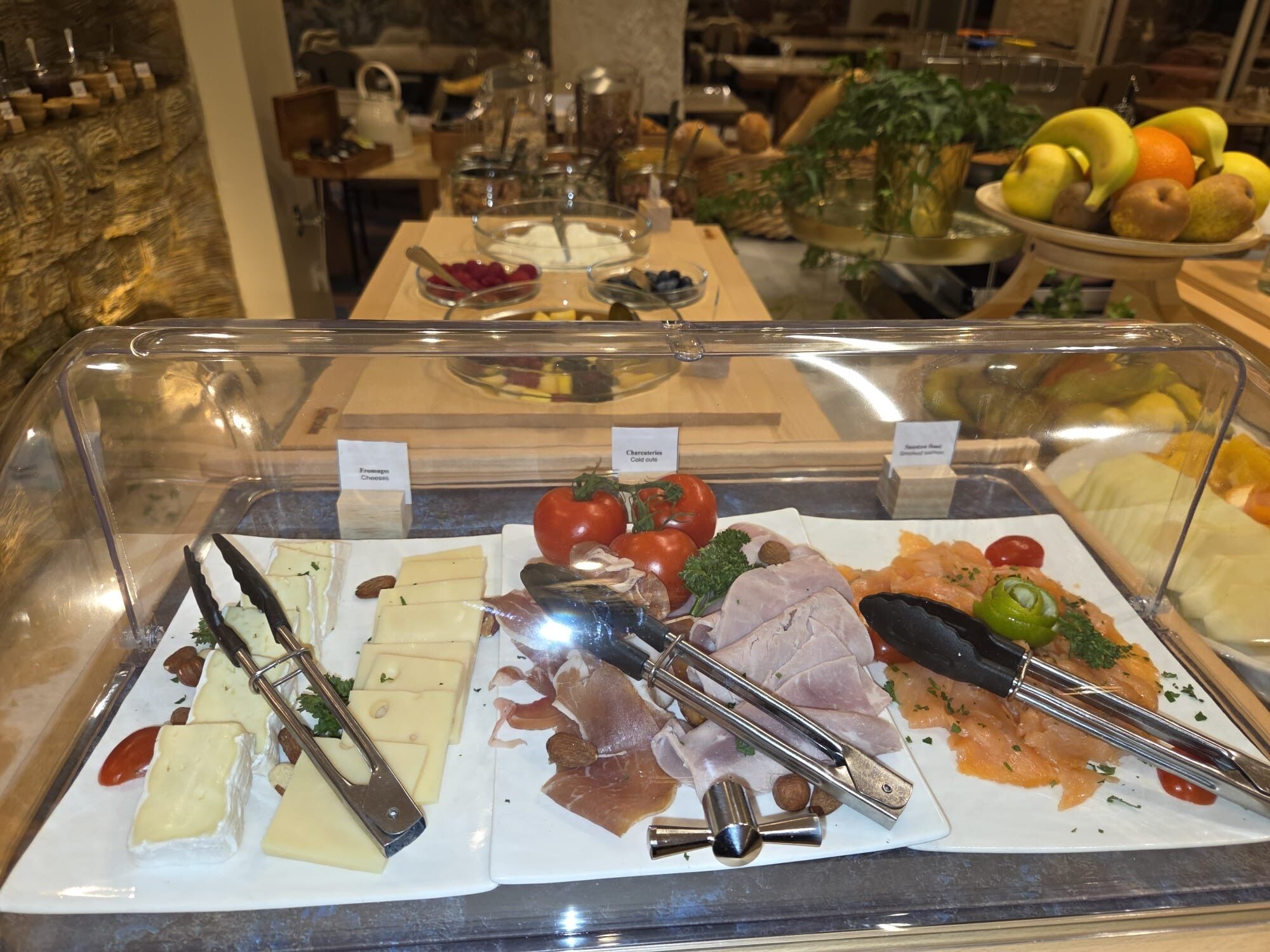 Um buffet com diversos queijos, carnes e frutas.