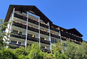 Um hotel de vários andares com varandas decoradas com flores e guarda-sóis amarelos.