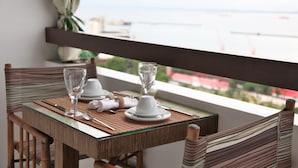Uma mesa de jantar com tampo de vidro, posta com pratos brancos, copos e talheres.