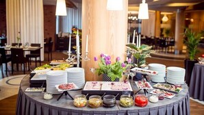 Disposição de buffet com diversos alimentos e um arranjo floral central.