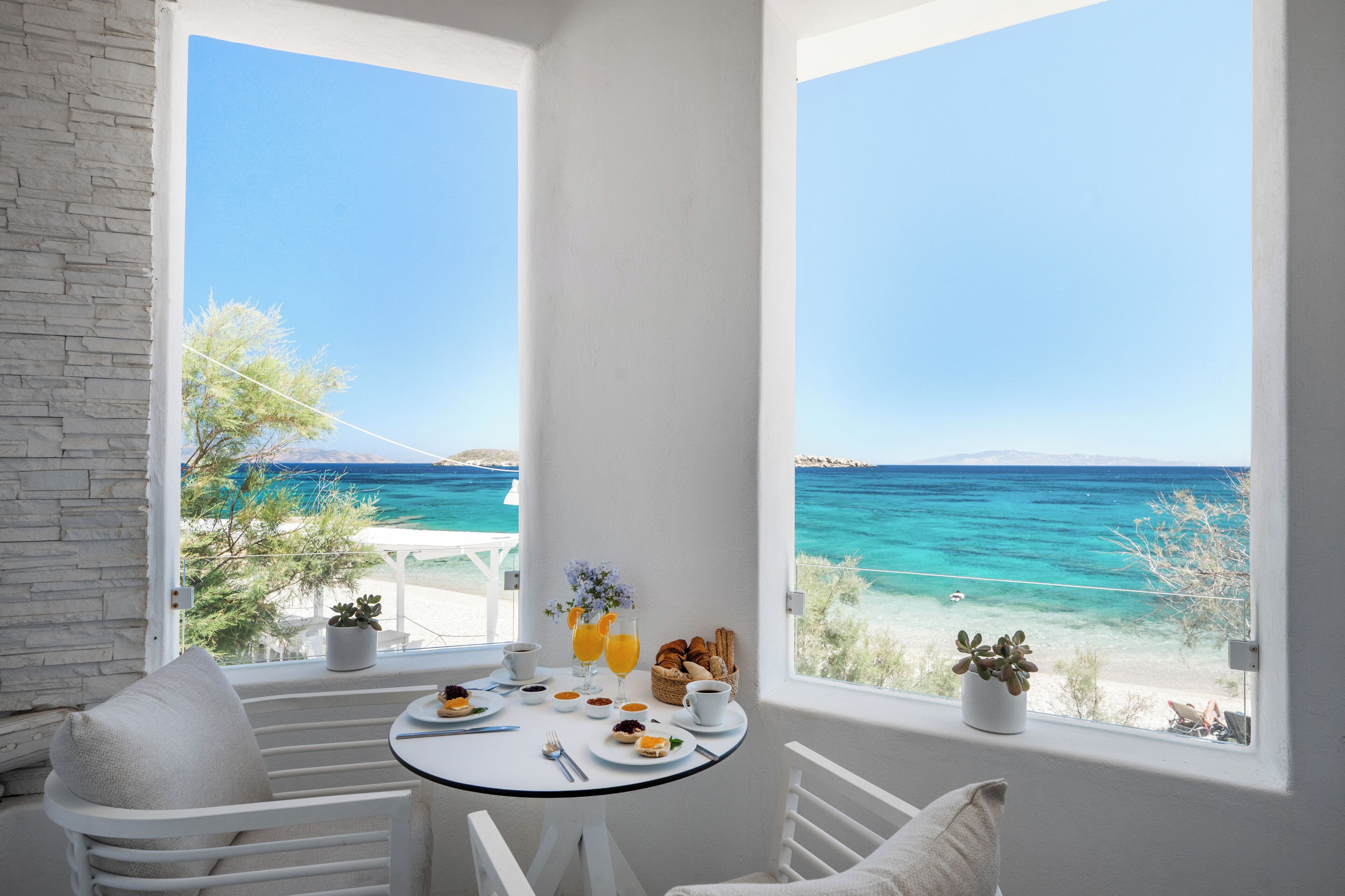 Uma mesa com itens de café da manhã e vista para o mar.