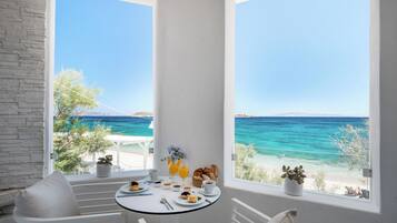 Uma mesa com itens de café da manhã e vista para o mar.