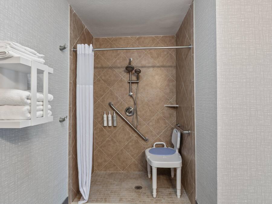 Casa de banho pequena e moderna com chuveiro, sanita e suporte para toalhas.
