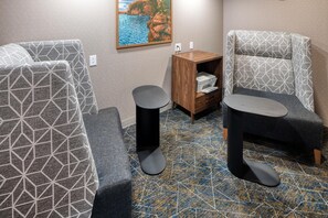 Um quarto com assentos estampados, um pequeno armário de madeira e um quadro na parede.