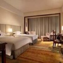 Quarto de hotel com duas camas, uma mesa e uma cadeira.