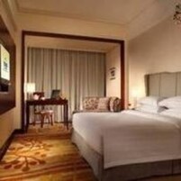 Quarto de hotel com uma cama grande, uma mesa de escritório com cadeira, televisão e janela com cortinas.