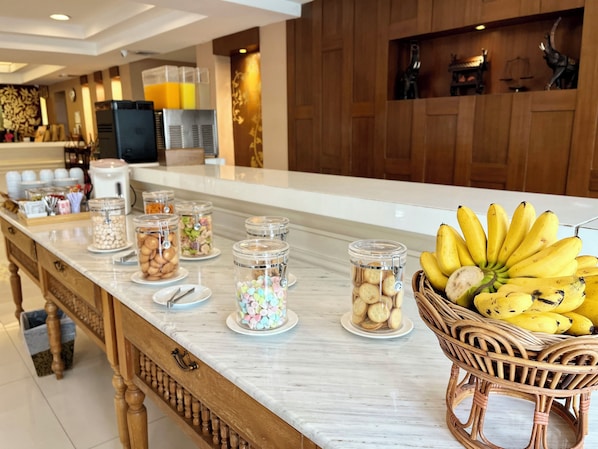 Disposição de buffet com diversos alimentos e uma cesta de vime com bananas.