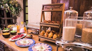 Buffet de café da manhã com diversos alimentos e um letreiro que diz "Pan Bread".