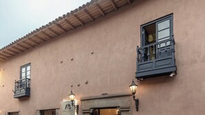 Um edifício com fachada de pedra, uma varanda com grades pretas e uma placa com a inscrição 