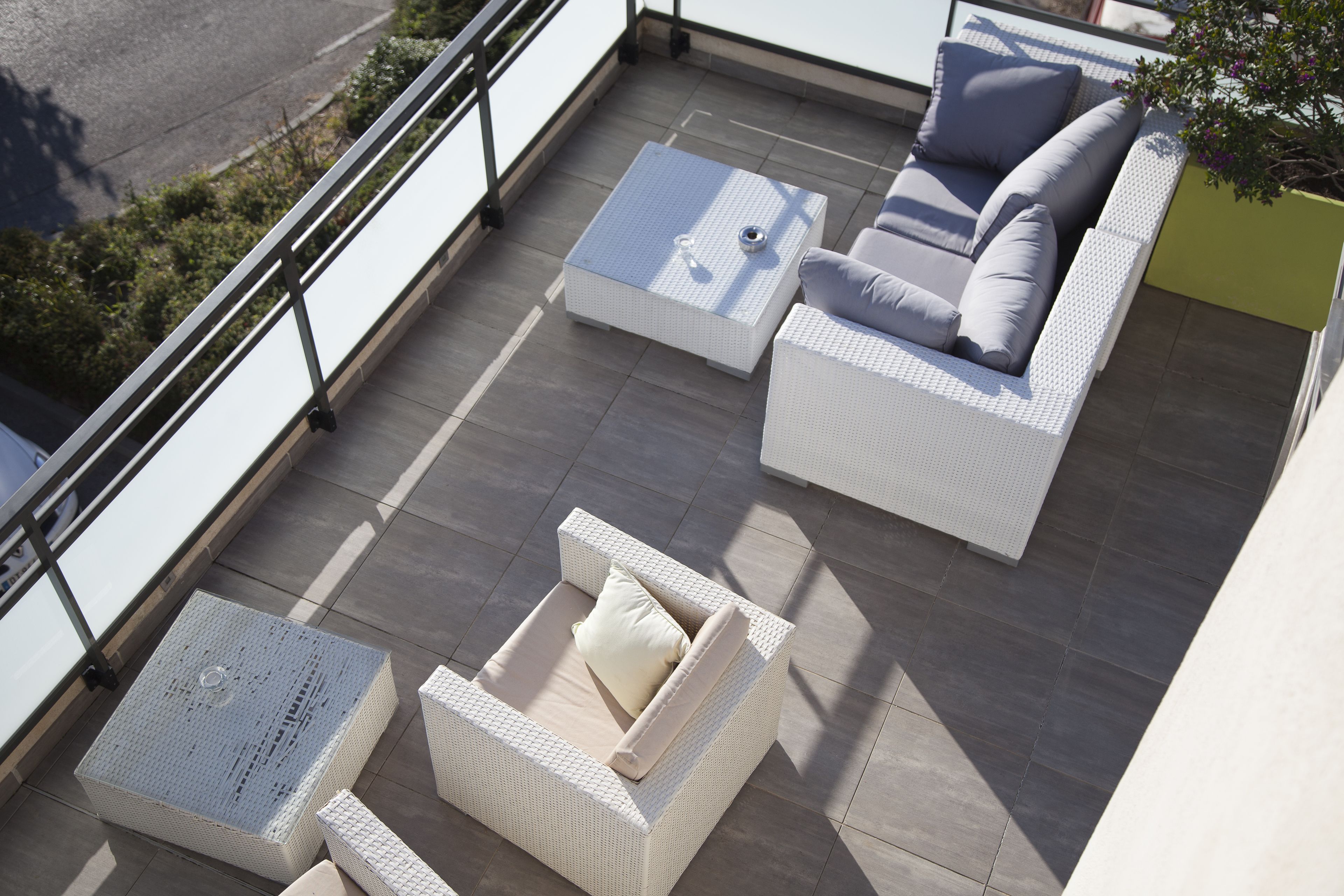 Terraço no telhado com um sofá de vime branco, uma mesa pequena e um banco acolchoado.