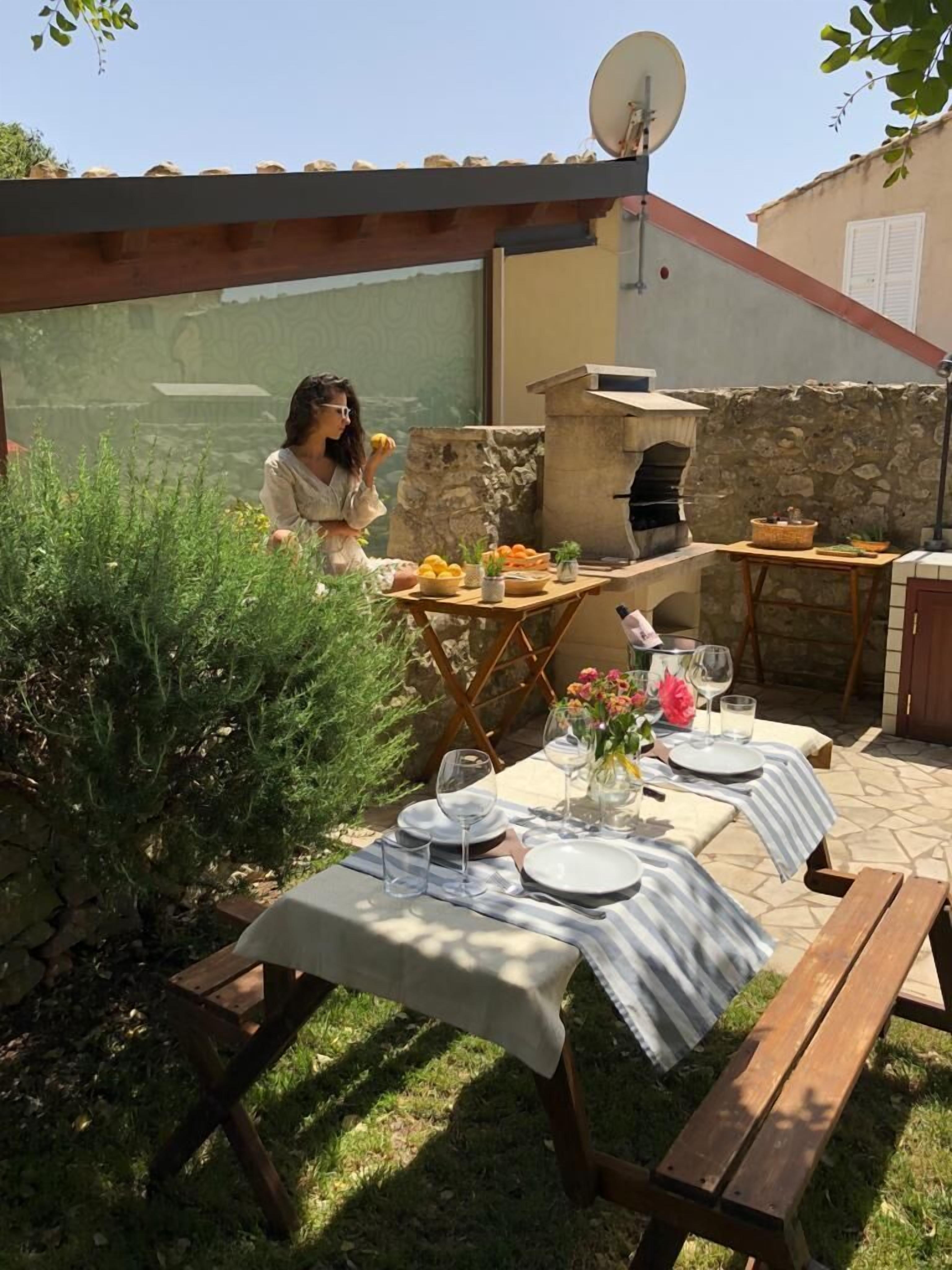 Uma área de refeições ao ar livre com parede de pedra, antena parabólica e forno a pizza.