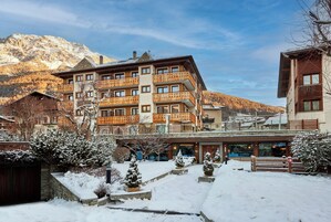 Um hotel de vários andares com varandas, um restaurante e um teleférico ao fundo.
