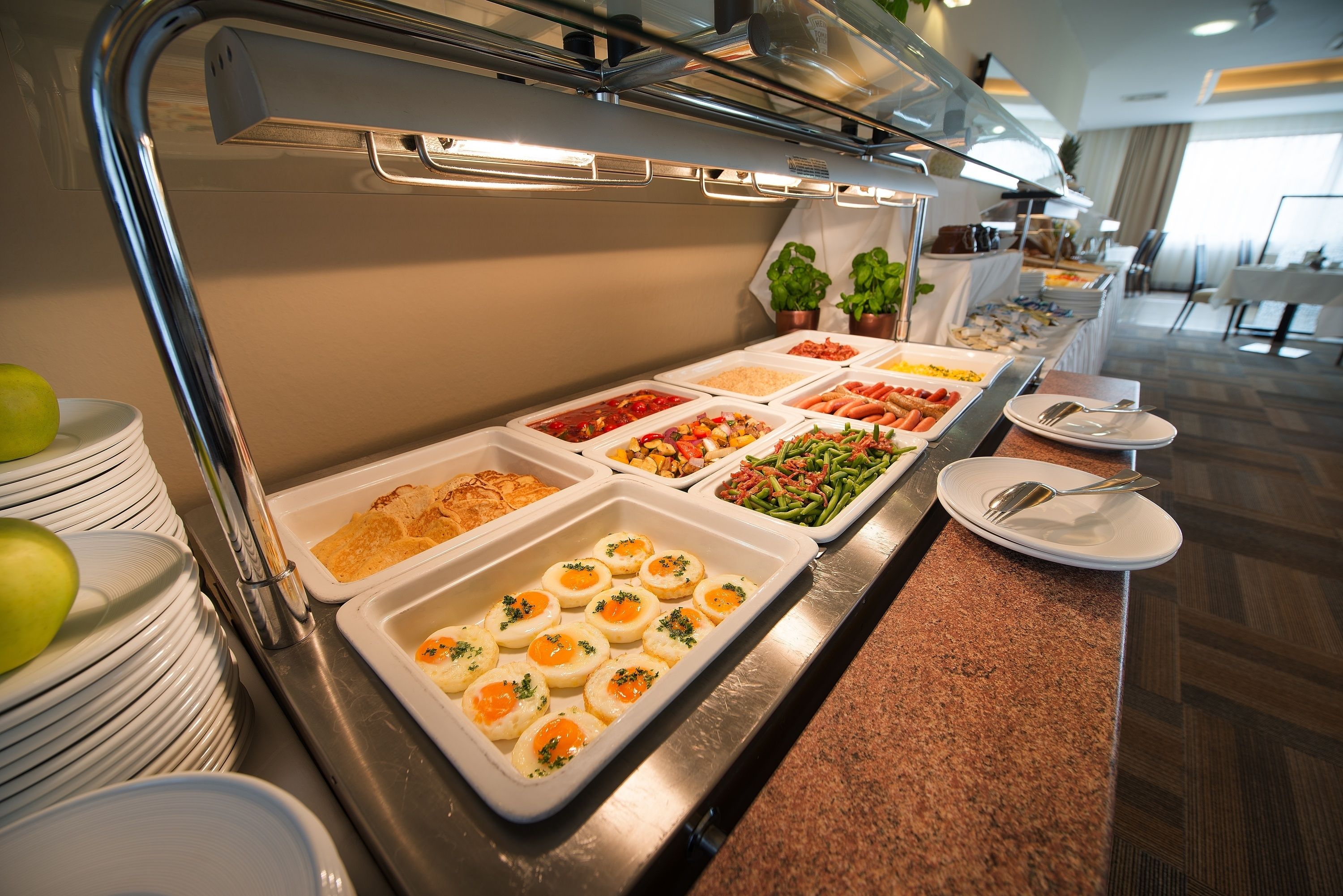 Buffet com diversas opções de comida, incluindo ovos, vegetais e carnes.