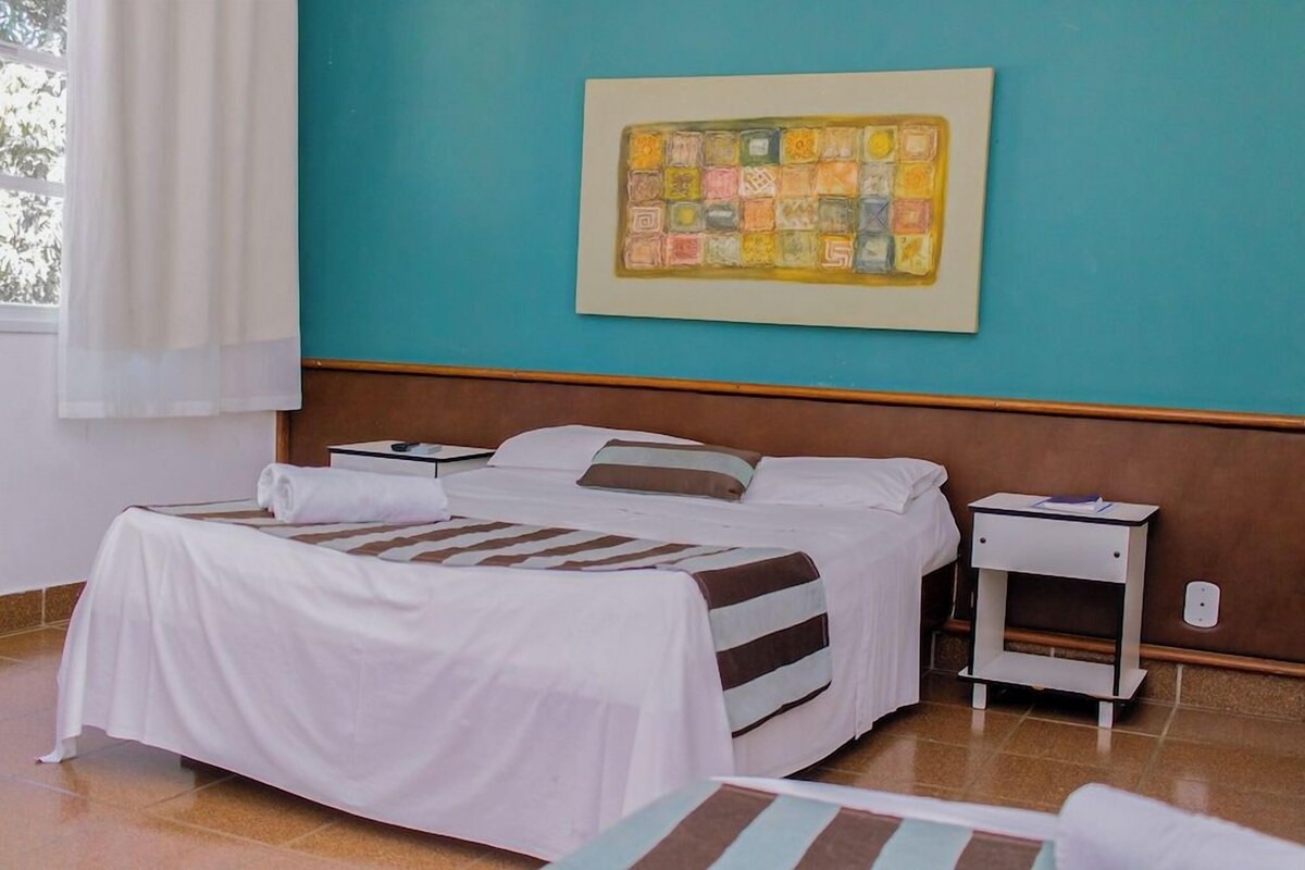 Quarto de hotel com cama, mesa de cabeceira e um quadro na parede.