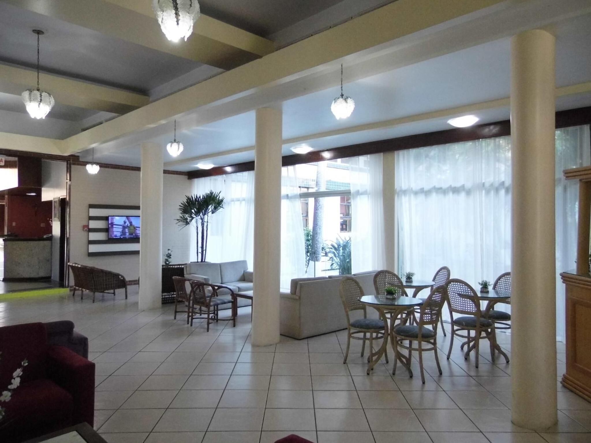 Amplo espaço interno com mesa e cadeiras de jantar, um sofá e uma televisão na parede.