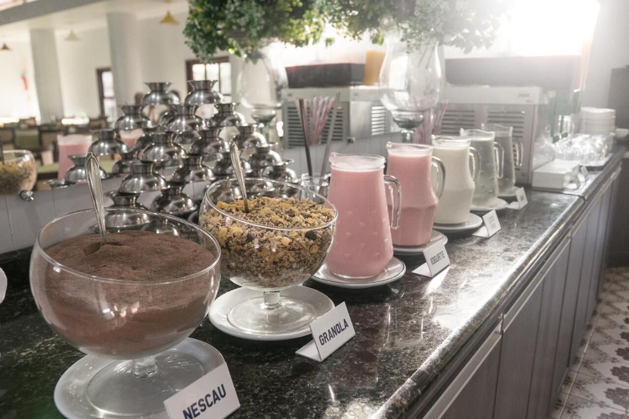 Buffet com diversos alimentos, incluindo sobremesa de chocolate, granola e smoothies cor-de-rosa.