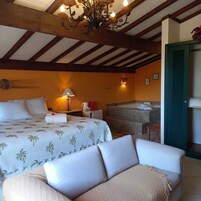 Quarto de hotel com duas camas, um espaço de estar, uma banheira e um candelabro.