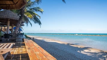 Na praia, areia branca, espreguiçadeiras, guarda-sóis