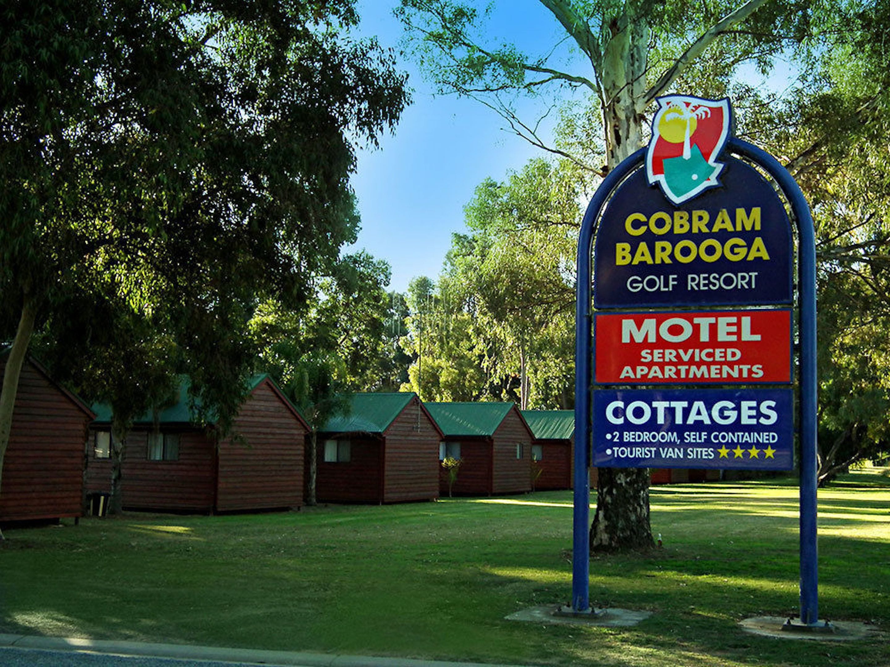 Placa para o COBRAM BAROOGA GOLF RESORT anunciando apartamentos de motel com serviço, chalés com 2 quartos, totalmente equipados e espaços para caravanas de turistas.