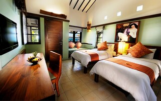 Quarto de hotel com duas camas, uma mesa de jantar de madeira, televisão e um quadro na parede.