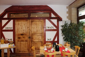 Uma área de jantar com madeira, teto alto, vigas de madeira e uma janela grande.